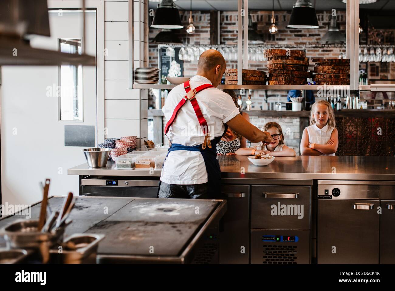 Girls watching chef working in restaurant kitchen Stock Photo - Alamy