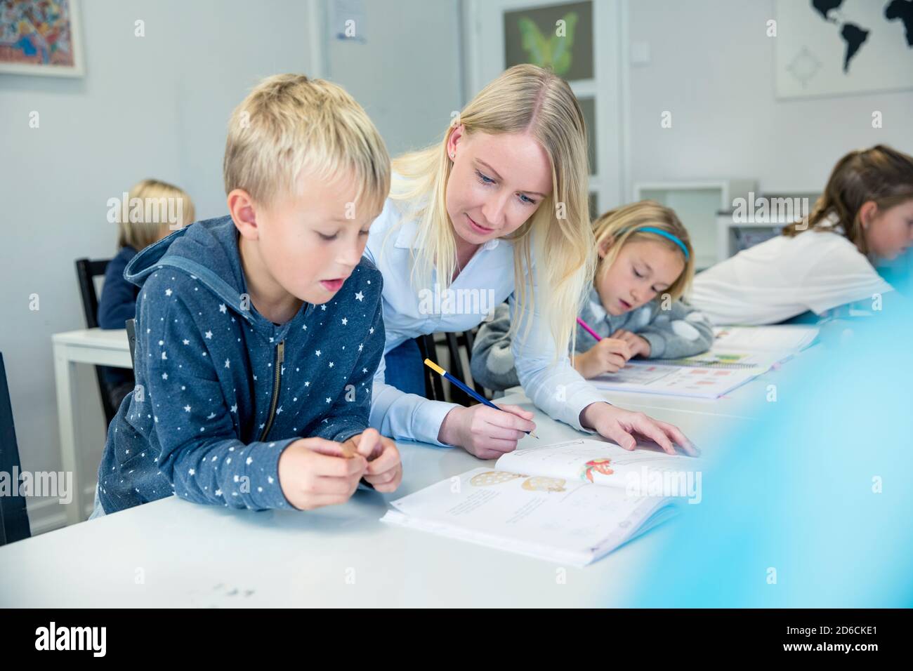 Teacher helping boy in classroom Stock Photo - Alamy