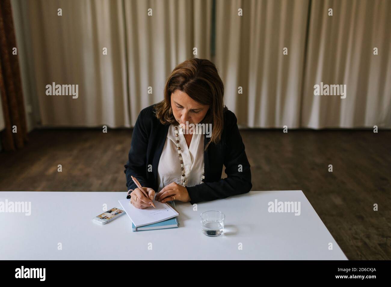 Woman at desk doing notes Stock Photo - Alamy