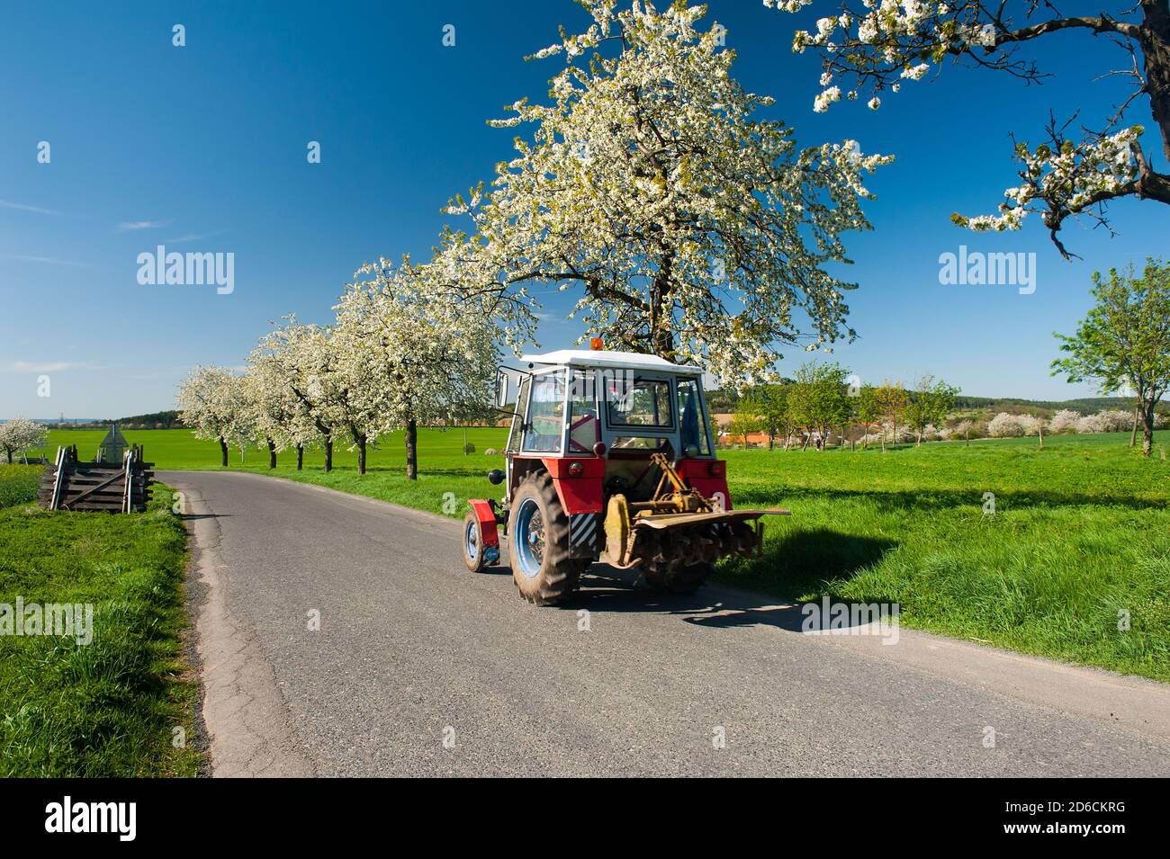 Tractor on the road in the spring country Stock Photo - Alamy