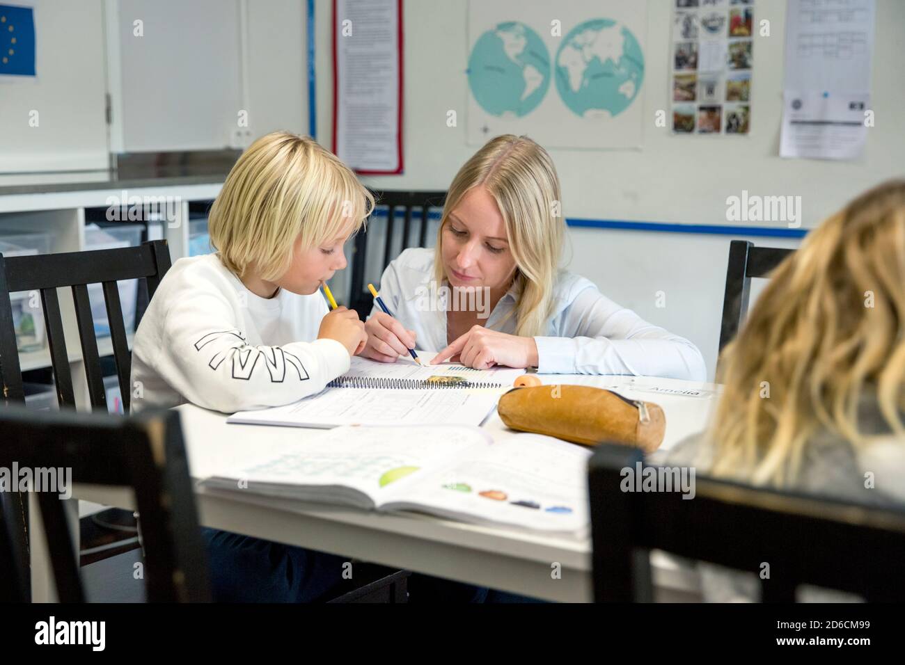 Teacher helping boy in classroom Stock Photo - Alamy