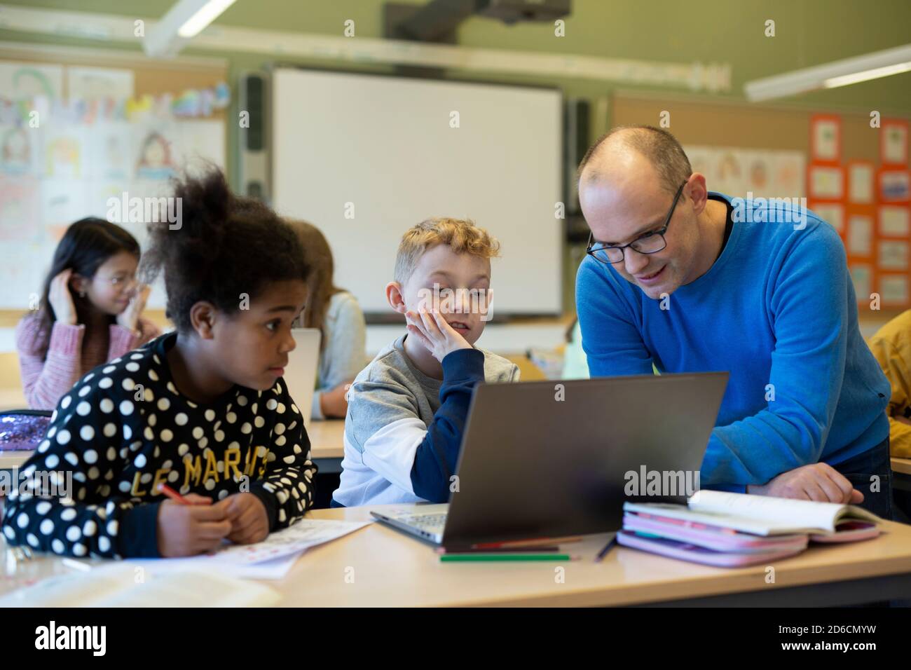 Teacher helping children in classroom Stock Photo - Alamy