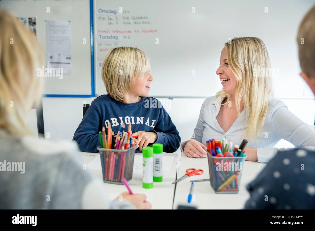 Teacher helping boy in classroom Stock Photo - Alamy