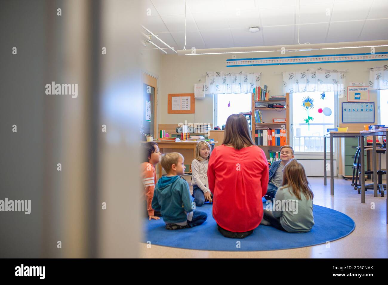 Teacher sitting on floor with children Stock Photo - Alamy
