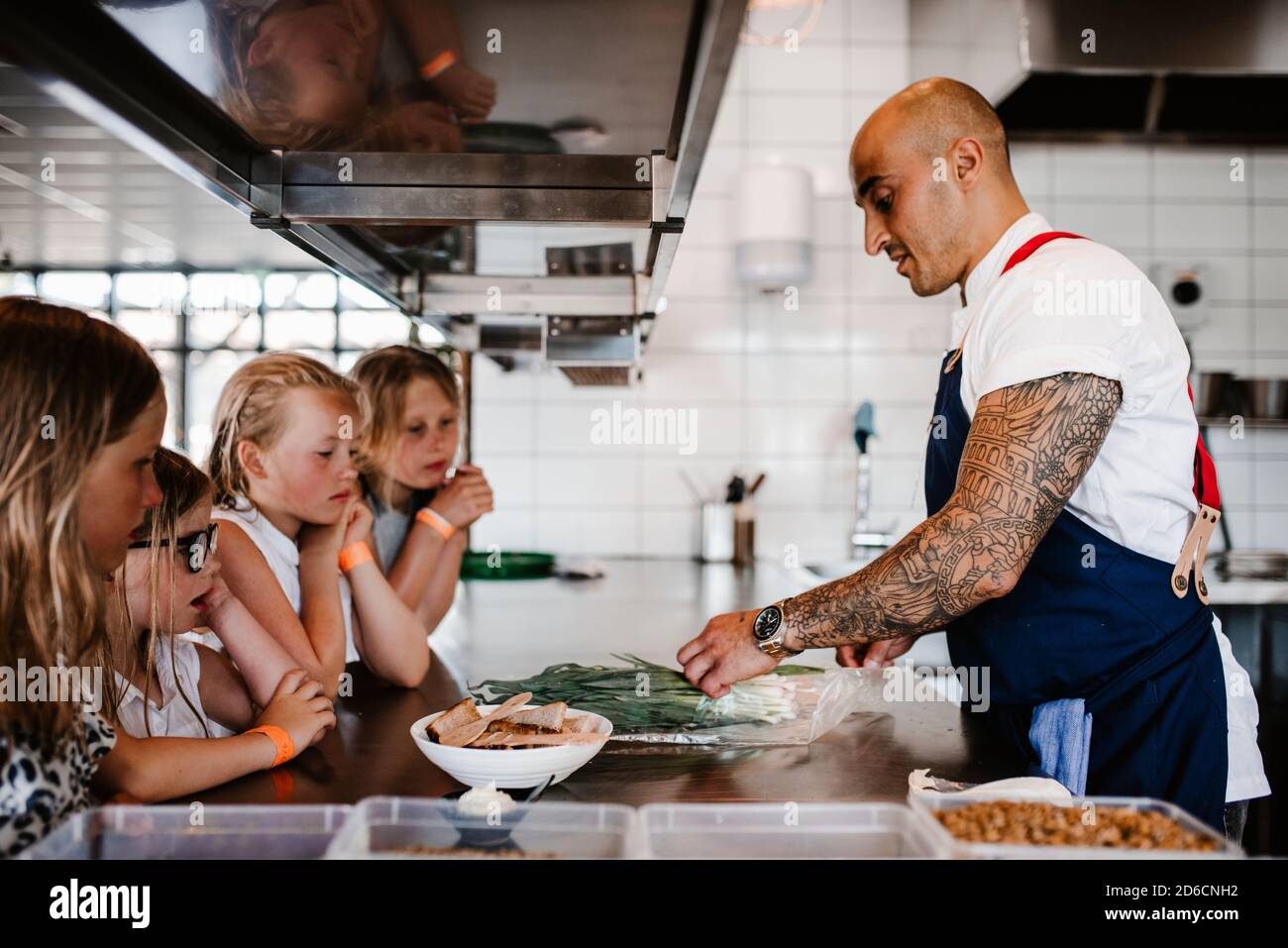 Girls watching chef working in restaurant kitchen Stock Photo - Alamy