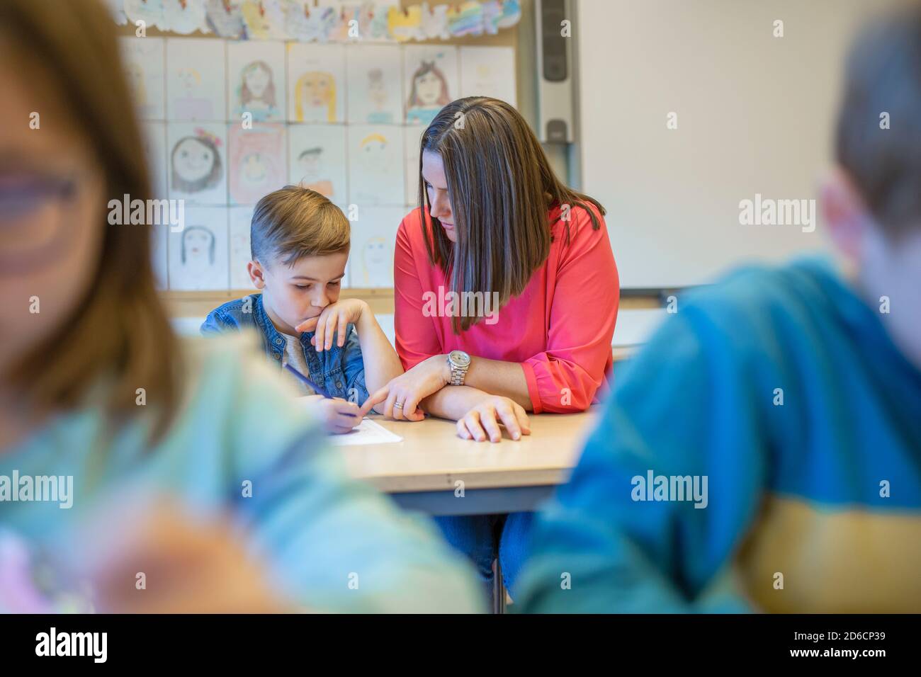 Teacher helping boy in classroom Stock Photo - Alamy
