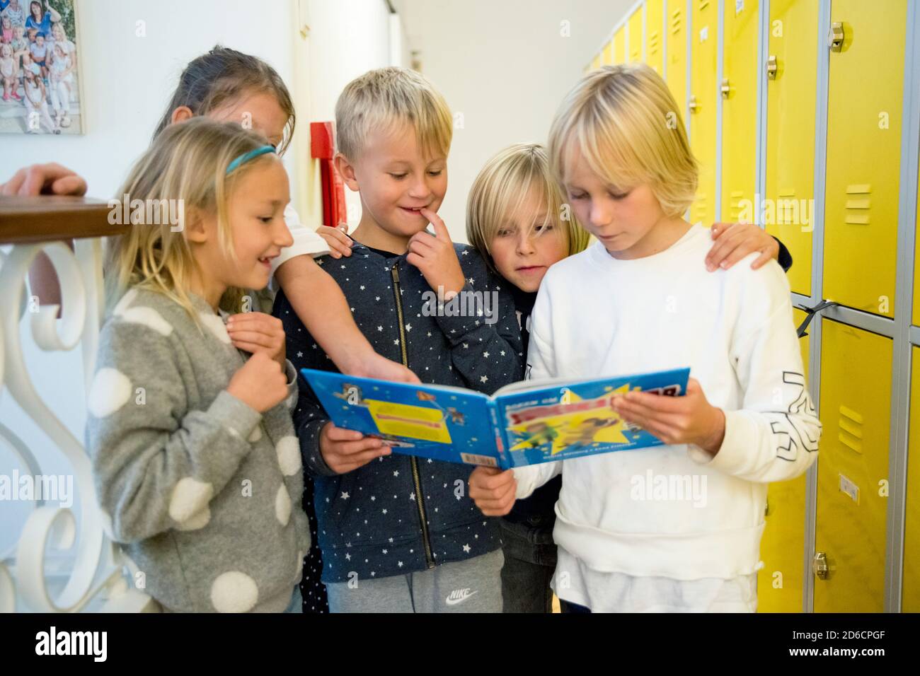 Kids looking at book together Stock Photo - Alamy