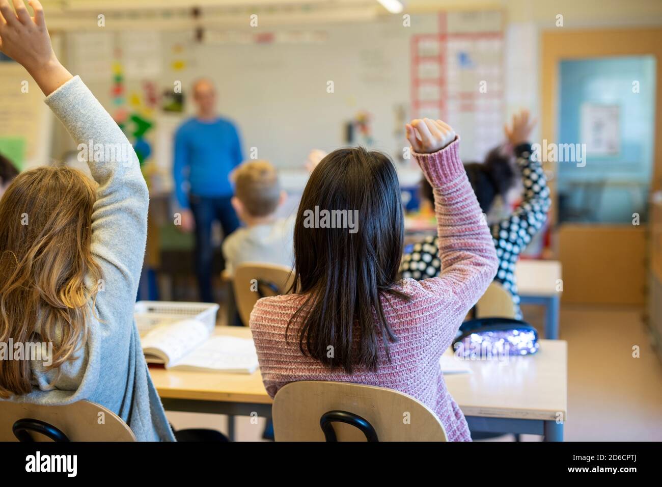 Girls raising hands in classroom Stock Photo - Alamy
