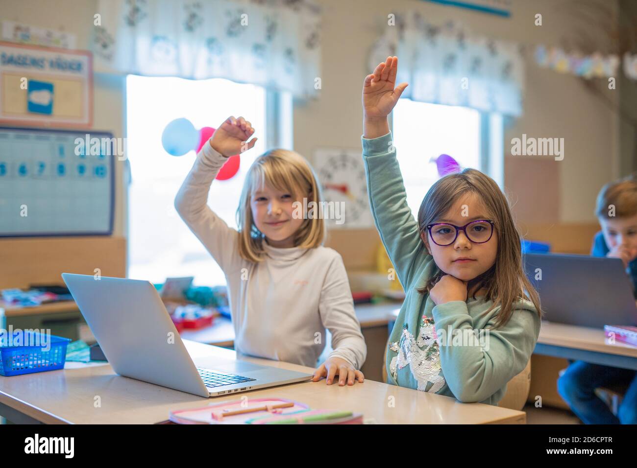 Girls raising hands in classroom Stock Photo - Alamy