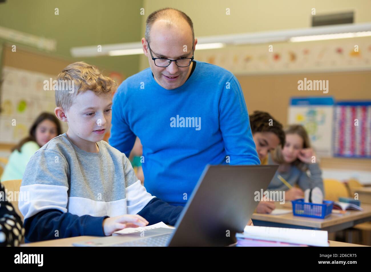 Teacher helping boy in classroom Stock Photo - Alamy