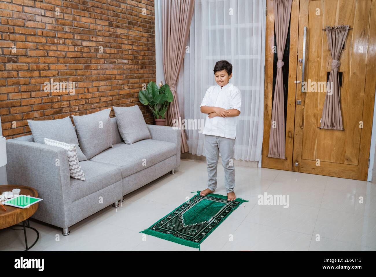 Muslim boy praying on rug at home Stock Photo - Alamy