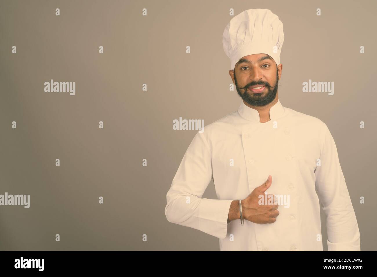 Young handsome Indian man chef against gray background Stock Photo - Alamy