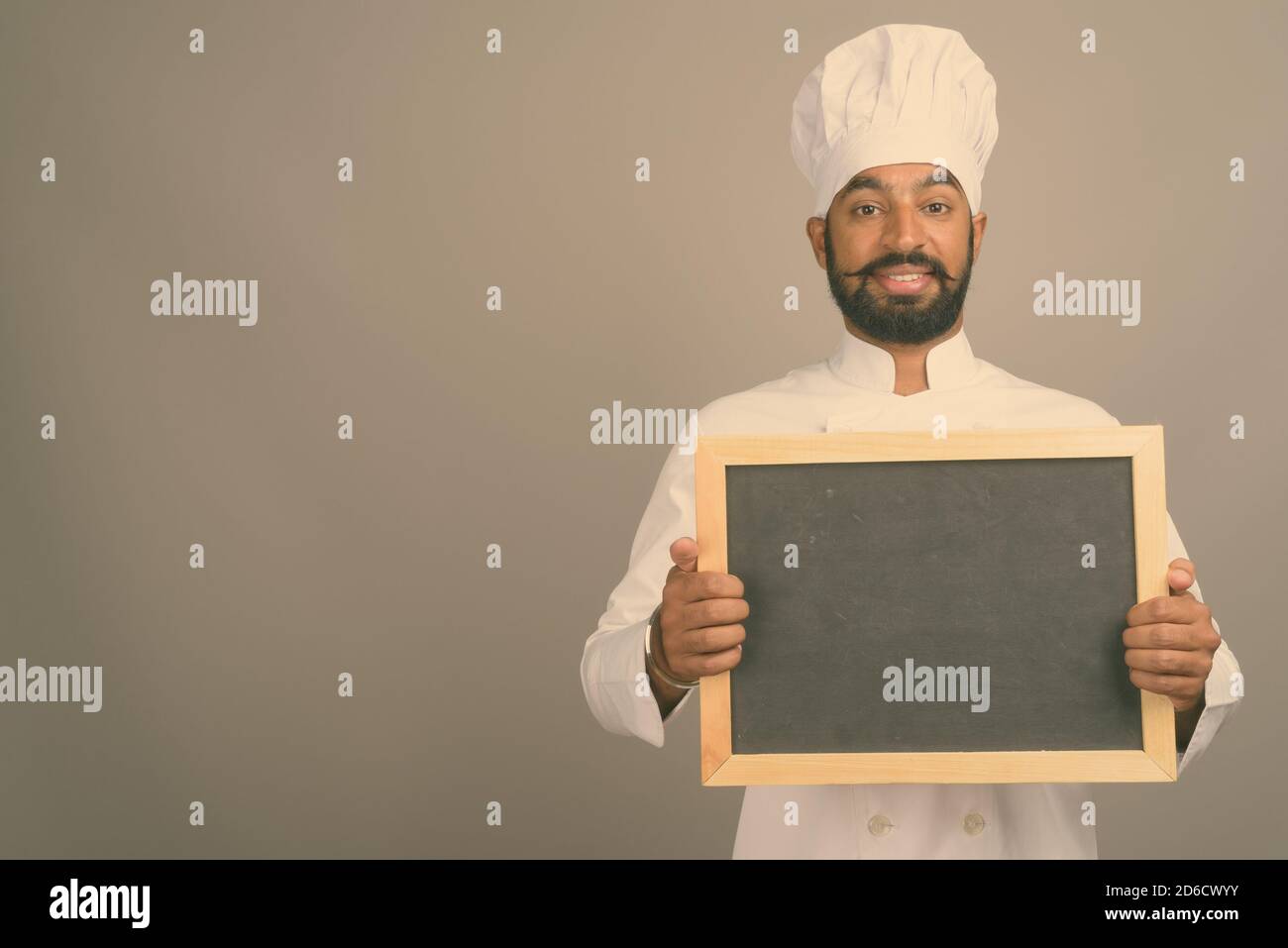 Young handsome Indian man chef against gray background Stock Photo - Alamy