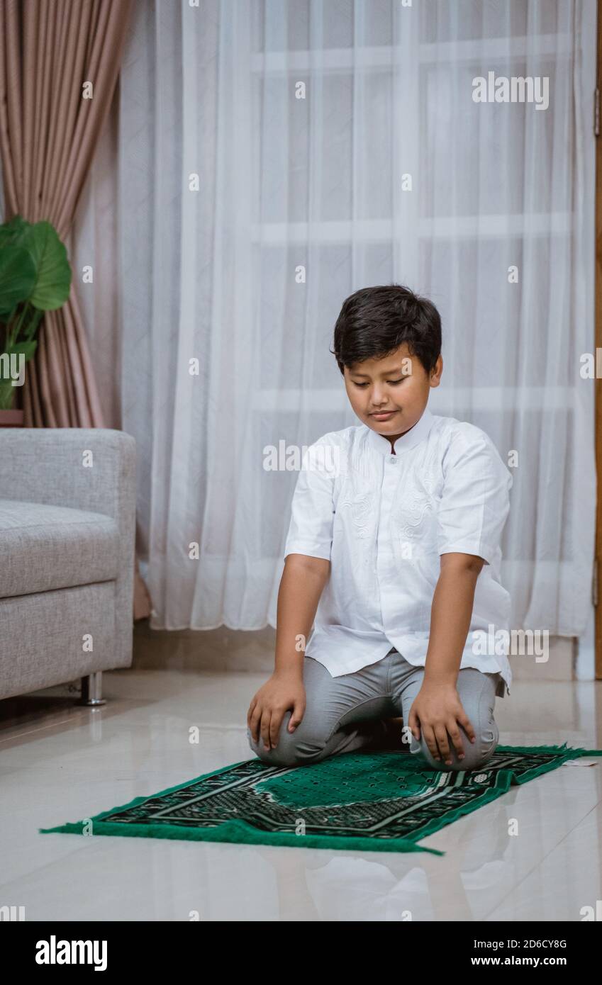 Religious Asian Muslim child standing praying to God on prayer mat ...
