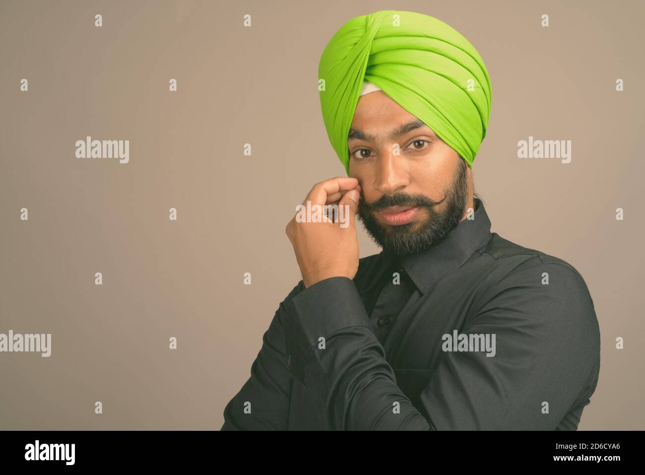 Young handsome Indian Sikh businessman wearing turban against gray ...