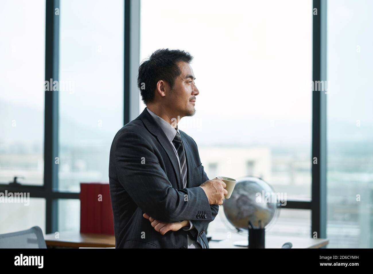 asian corporate executive thinking in office with a cup of coffee in ...