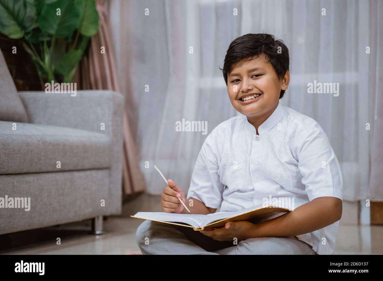 smiling muslim boy reading holy prayer book sit on prayer mat Stock ...
