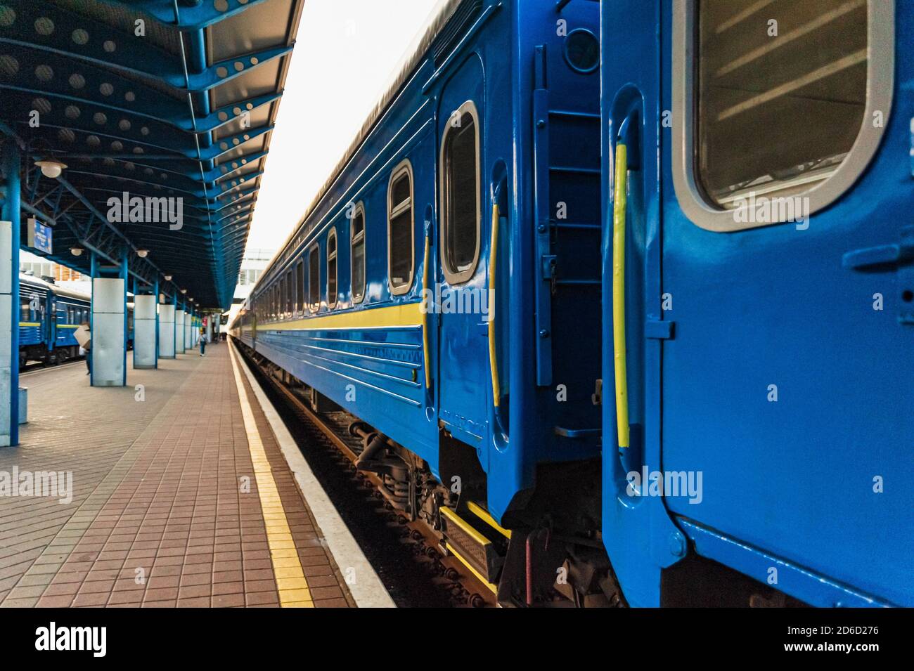 A train of blue railroad passenger cars stands near the platform at the ...