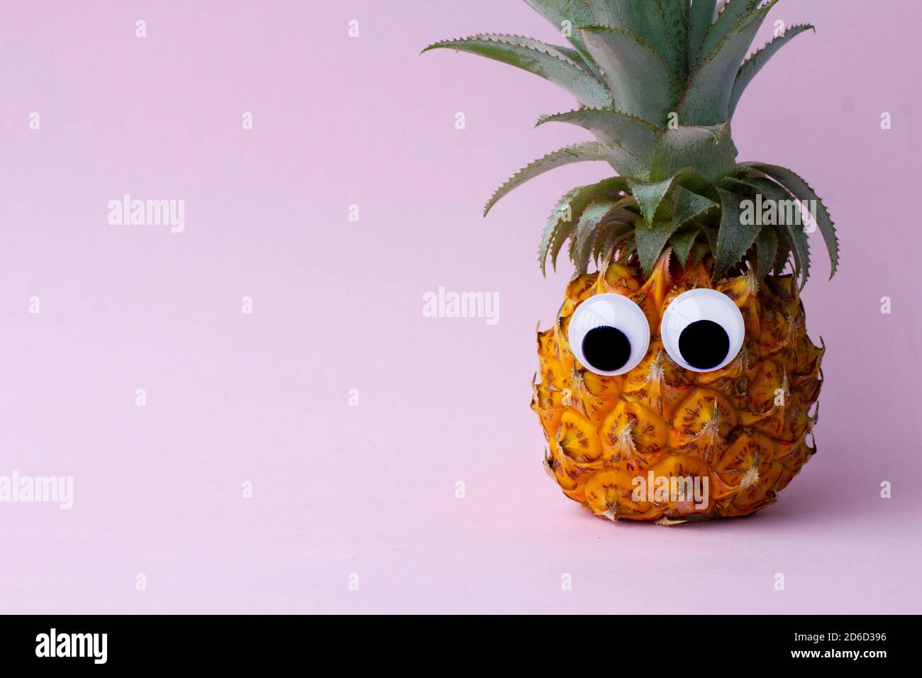 Funny exotic pineapple with googly eyes on pink background Stock Photo ...
