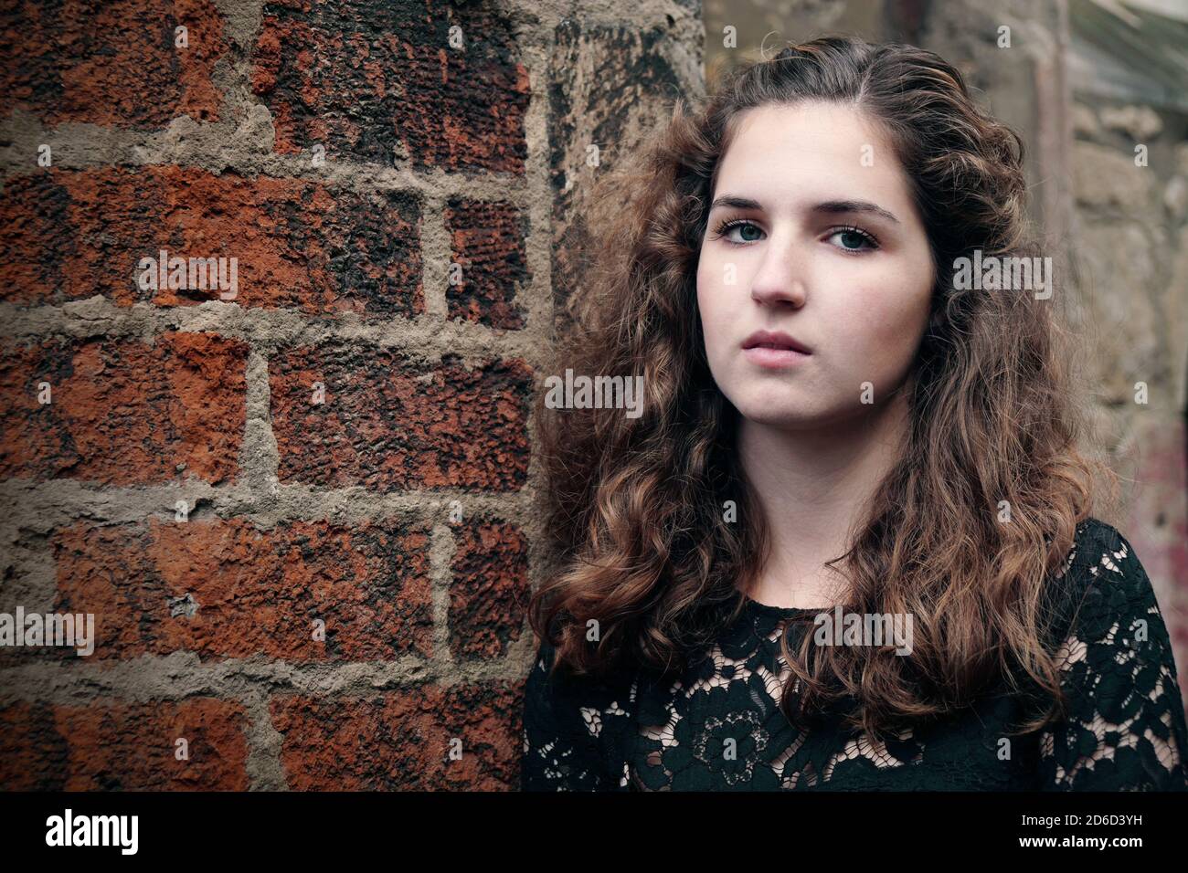 young woman leaning against old brick wall with copyspace Stock Photo ...