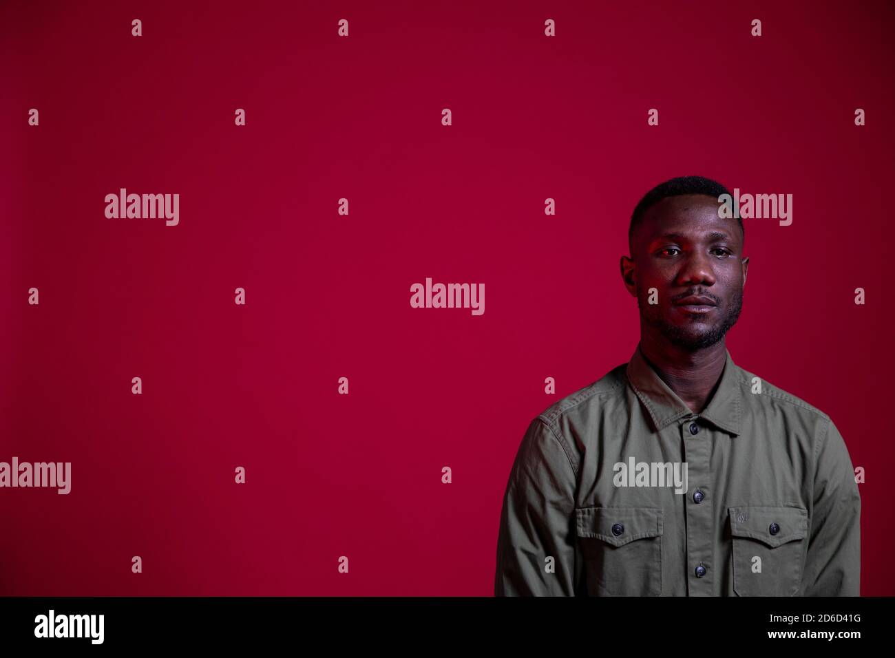Young black man posing in studio on isolated red background with copy ...