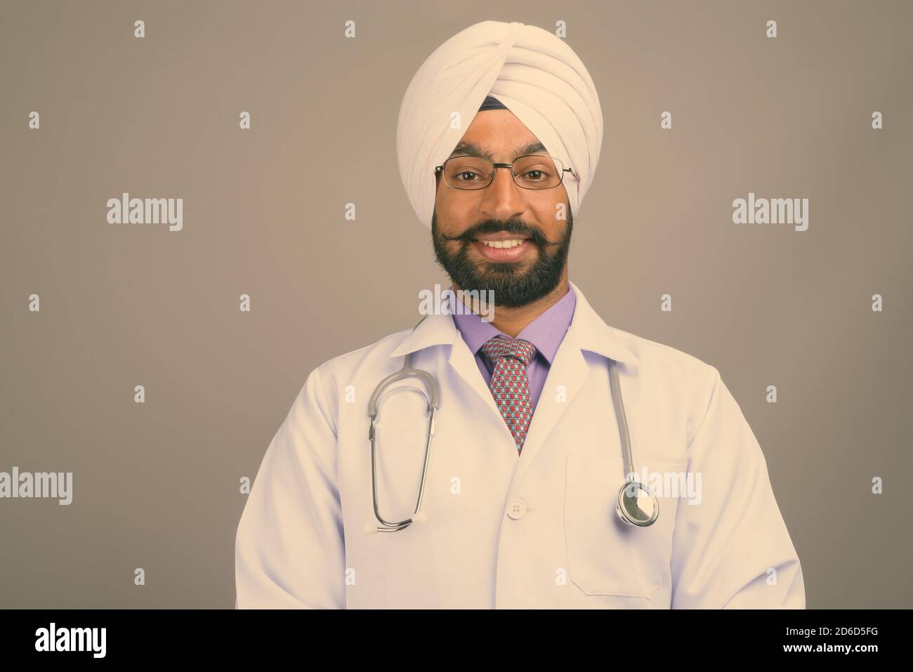 Young handsome Indian Sikh man doctor against gray background Stock ...