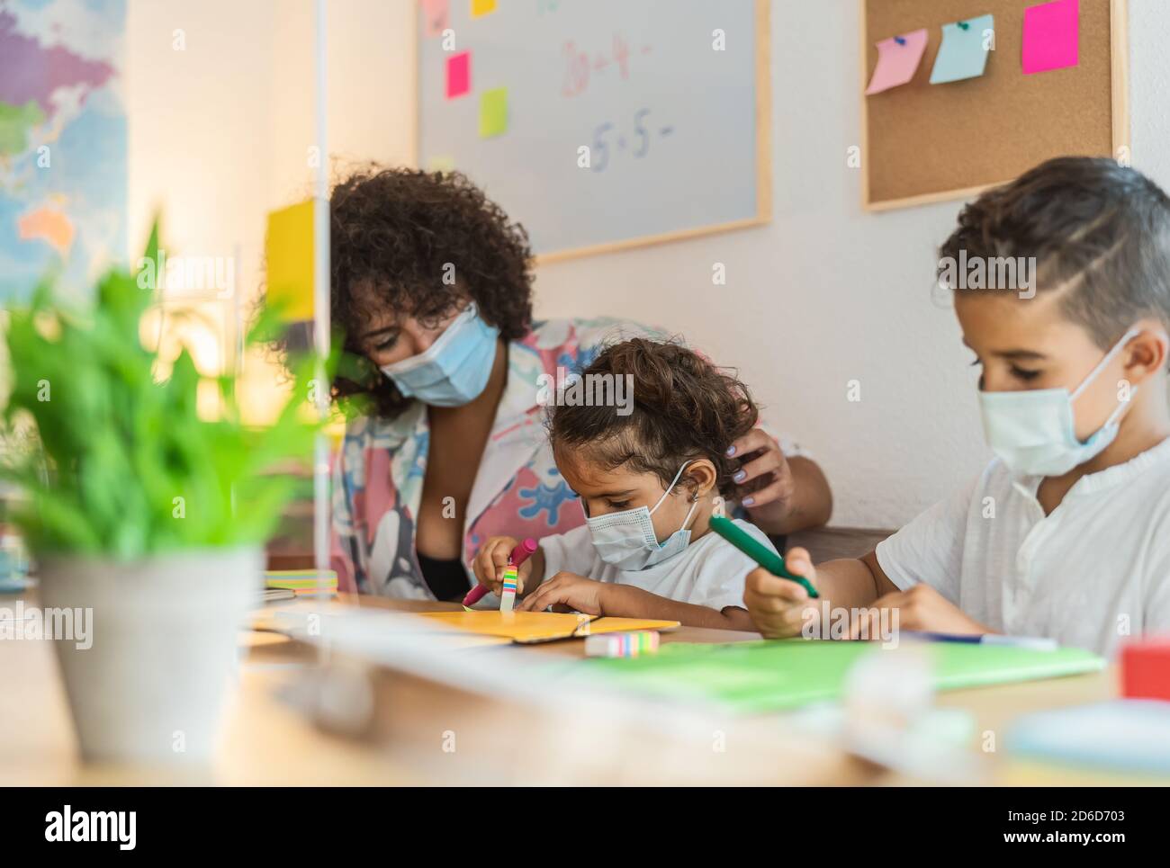Teacher with children wearing face mask in preschool classroom during ...