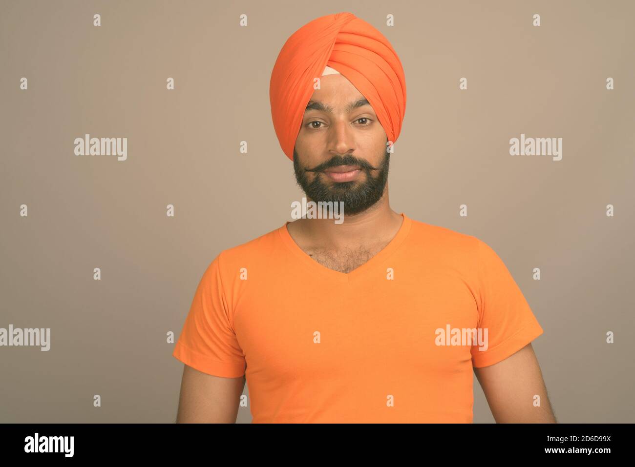 Young handsome Indian Sikh man wearing turban against gray background ...