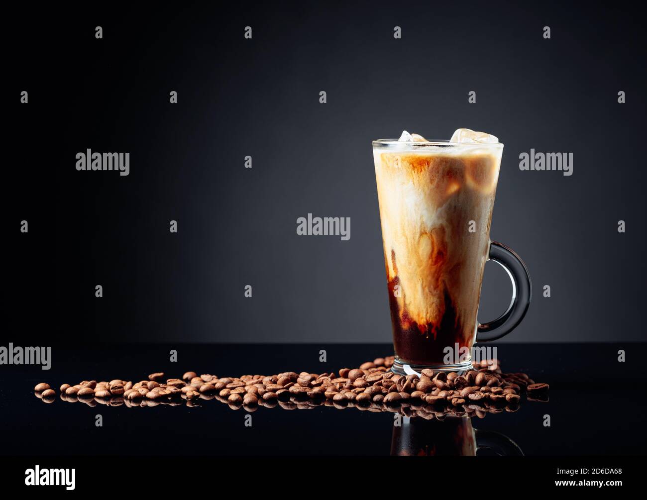 Ice coffee in frozen glass and coffee beans on a black reflective ...
