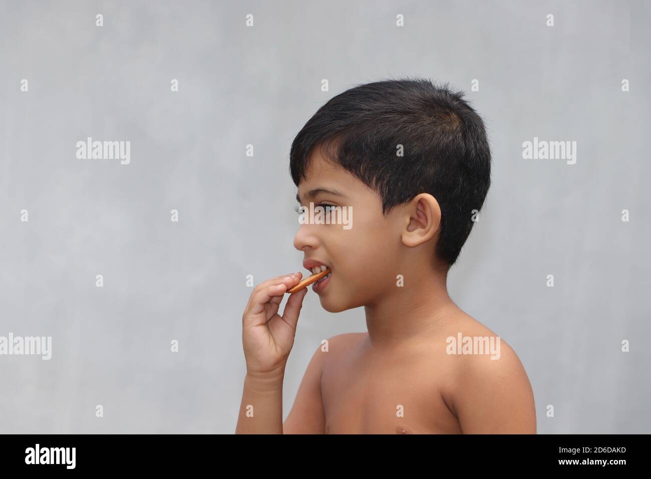 Cute little bare chested boy eating biscuits. Baked and processed food ...