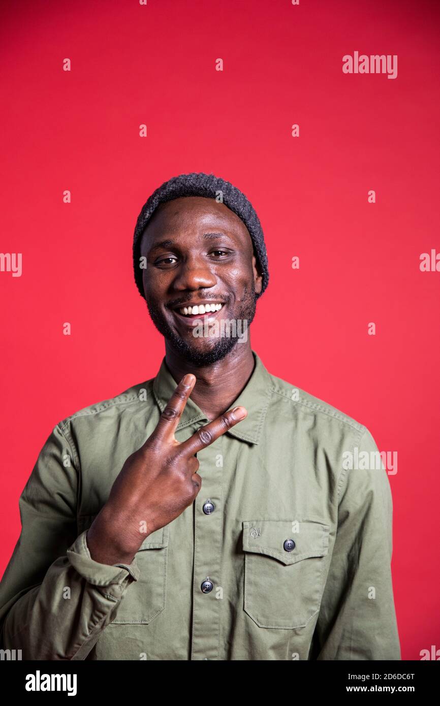 Young black man with toothy smile showing the peace sign. Isolated ...