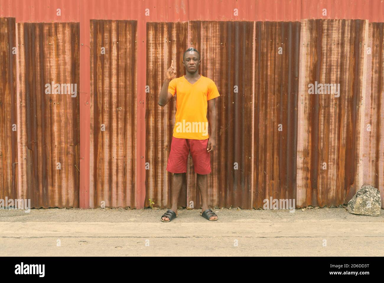 Young black African man standing while pointing finger up against old ...