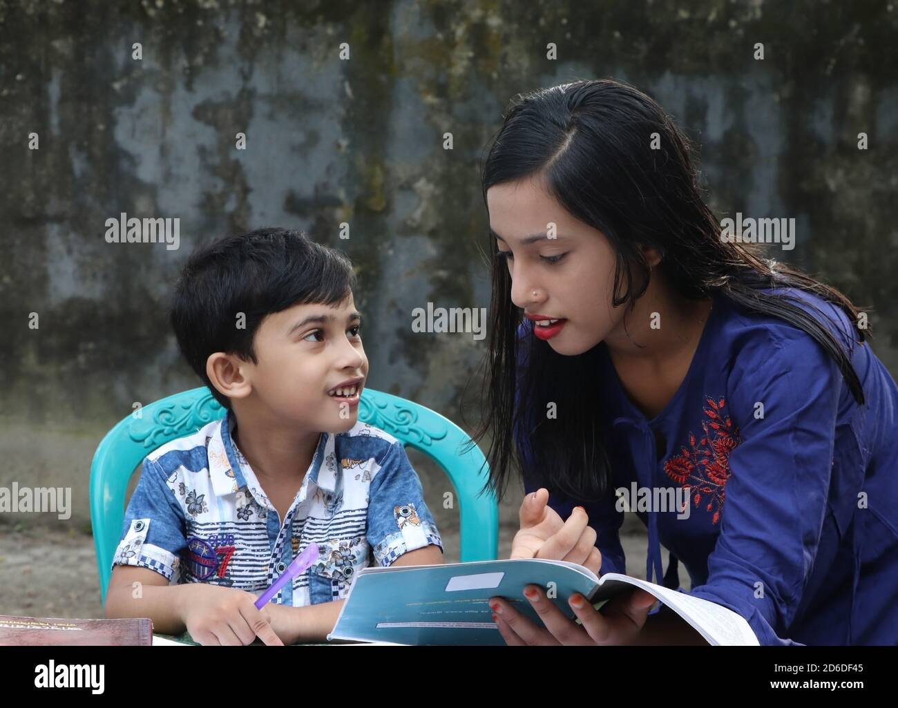 Sister helping her younger brother in study. Sister reading and ...