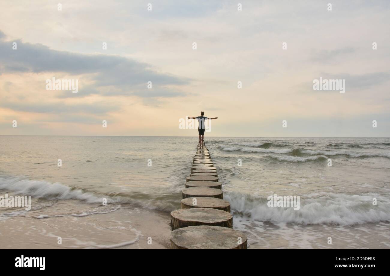 A lonely person stands on the edge of a cliff and looks at the sea ...