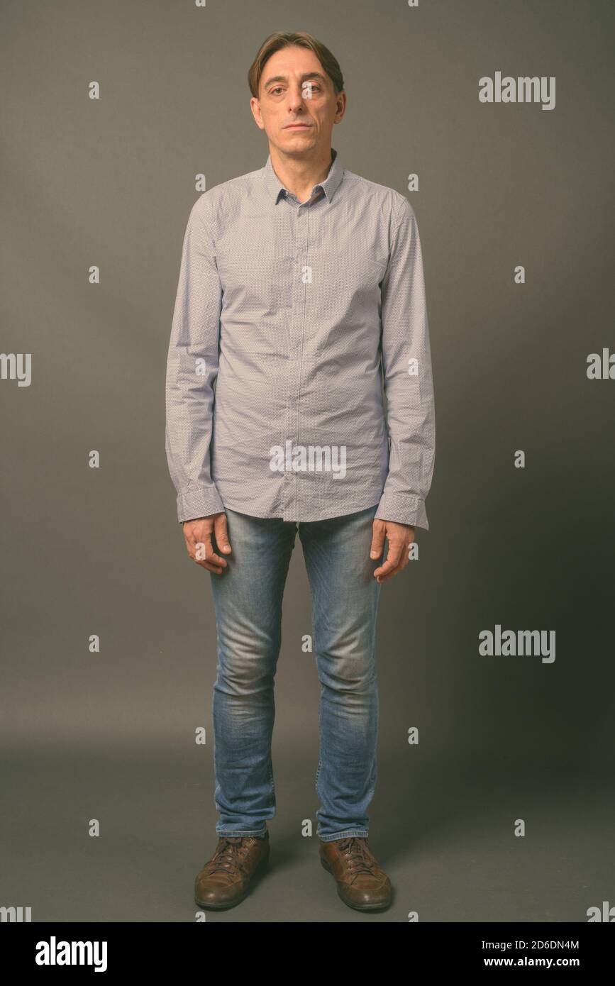 Mature handsome Italian man against gray background Stock Photo - Alamy