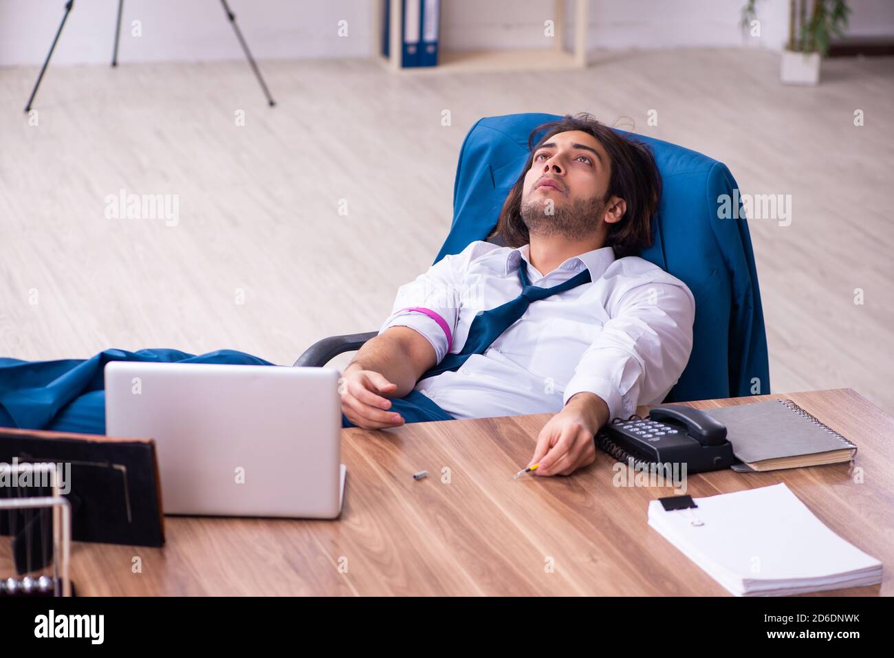 Drug addicted employee working in the office Stock Photo - Alamy