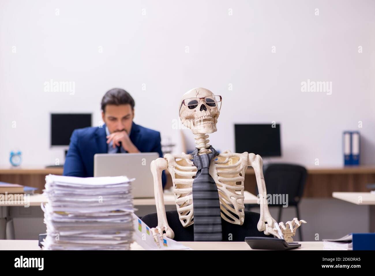 Young employee with skeletons in the office Stock Photo - Alamy