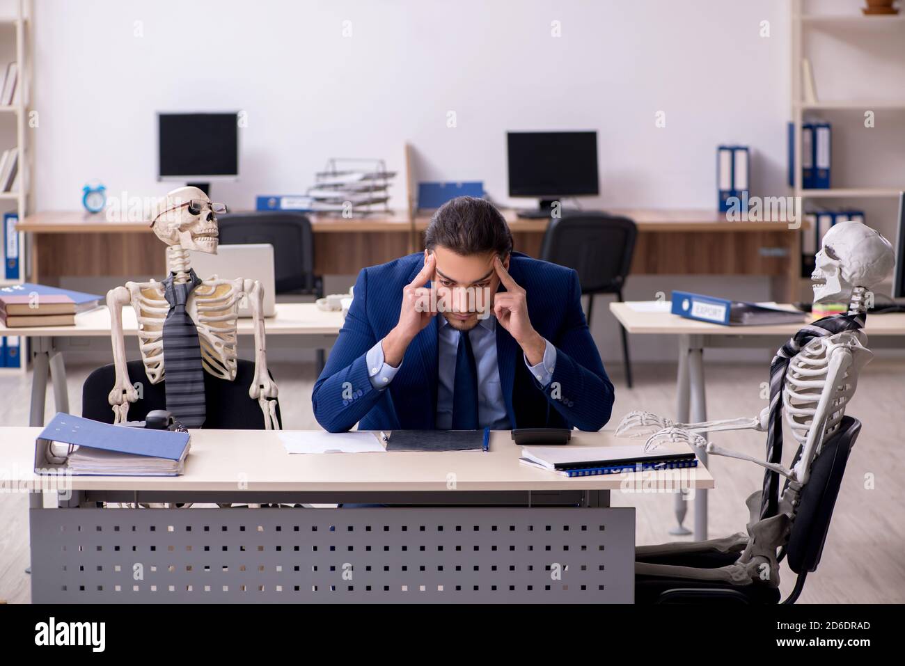 Young employee with skeletons in the office Stock Photo - Alamy
