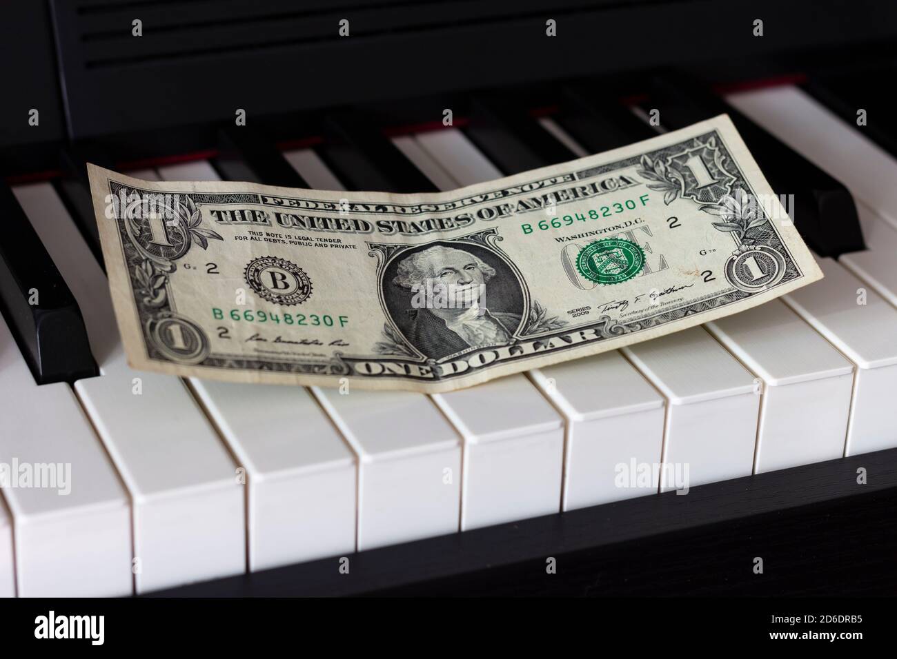 One dollar banknote lying on the piano keys. The dollar as a symbol of ...