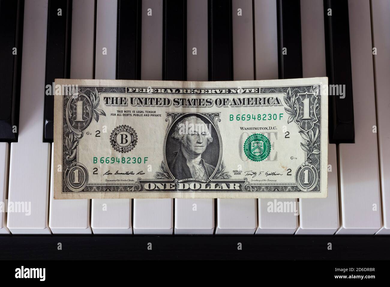 One dollar banknote lying on the piano keys. The dollar as a symbol of ...