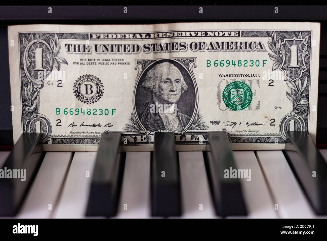 One dollar banknote lying on the piano keys. The dollar as a symbol of ...