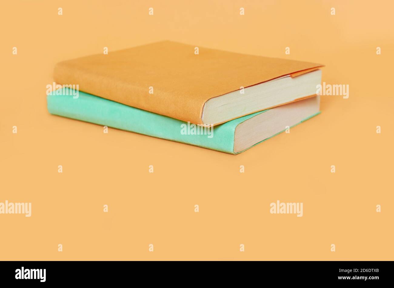Two books with colored covers are on a uniform orange background Stock ...