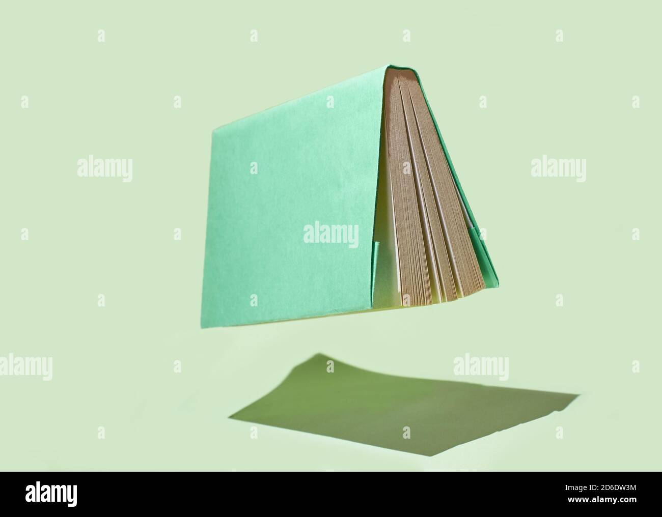 Levitating book in a color cover on a uniform green background with a ...
