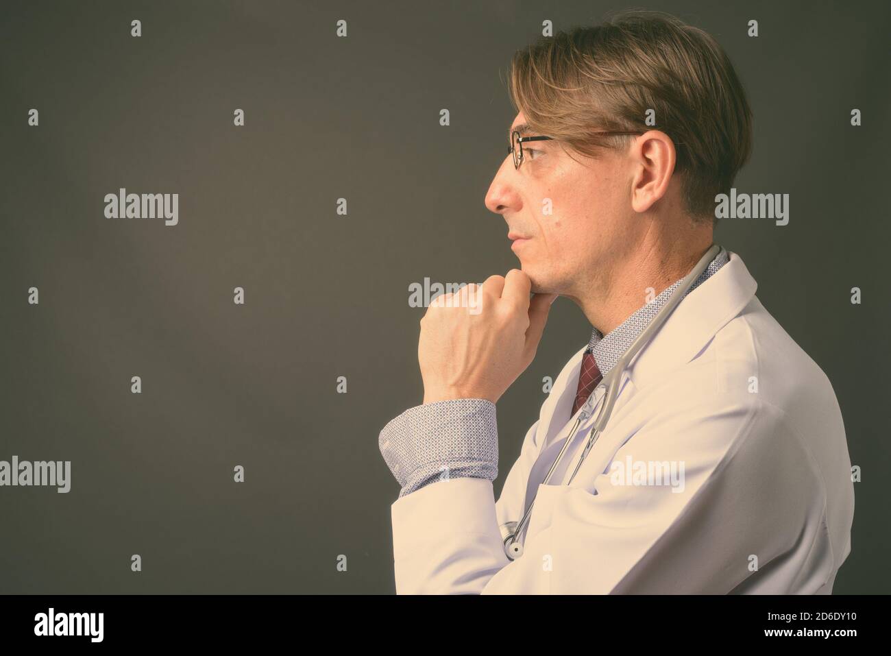 Mature handsome Italian man doctor against gray background Stock Photo ...
