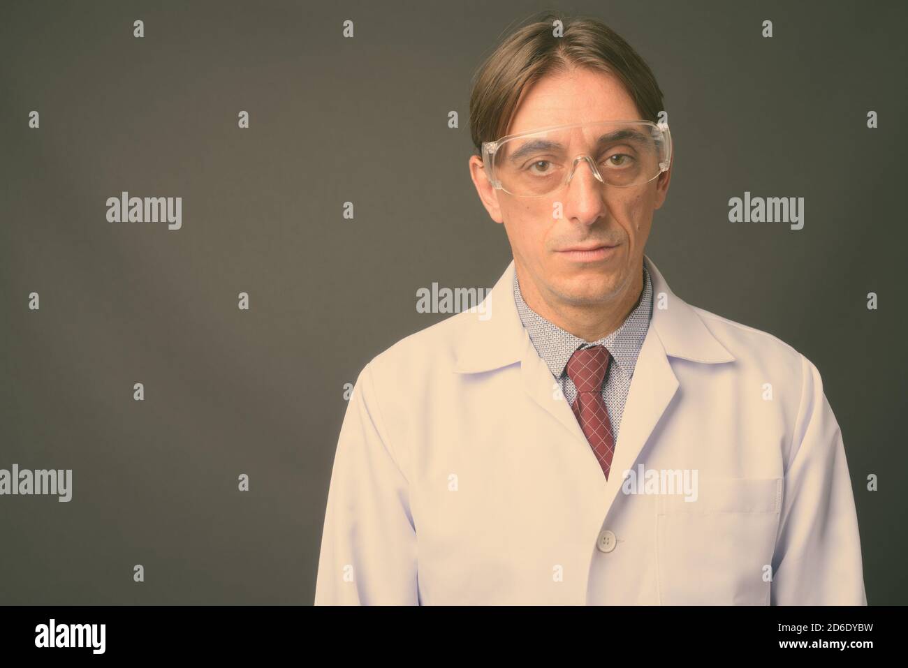 Mature handsome Italian man doctor wearing protective glasses against ...