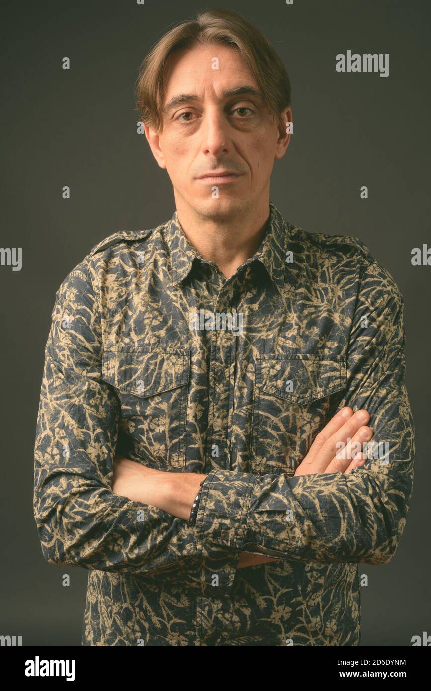 Mature handsome Italian man against gray background Stock Photo - Alamy