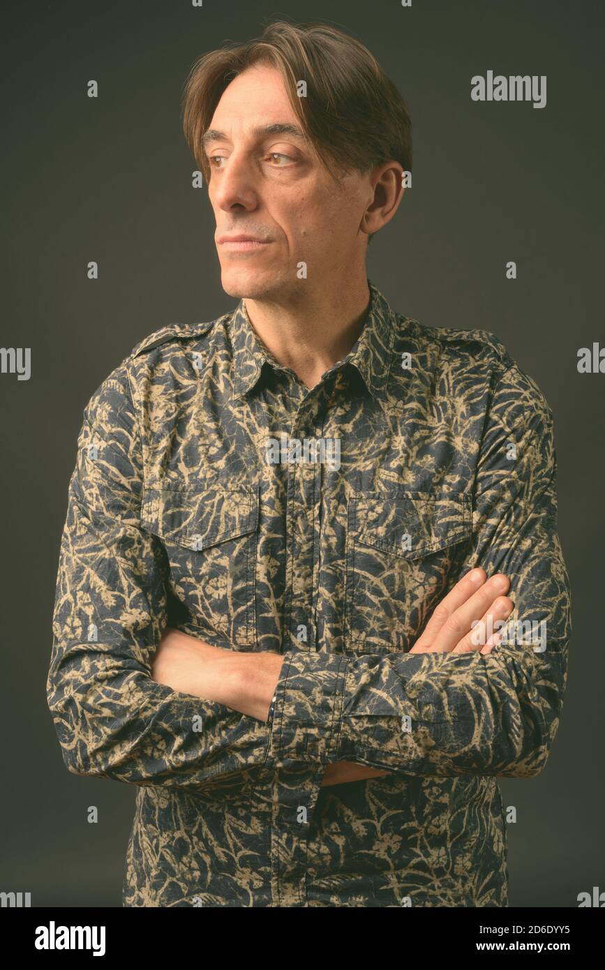 Mature handsome Italian man against gray background Stock Photo - Alamy