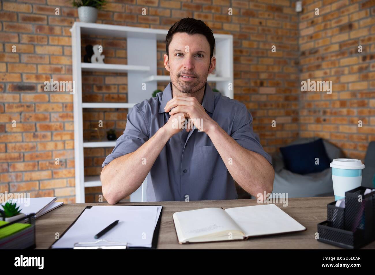 Portrait of man sitting on his desk Stock Photo - Alamy