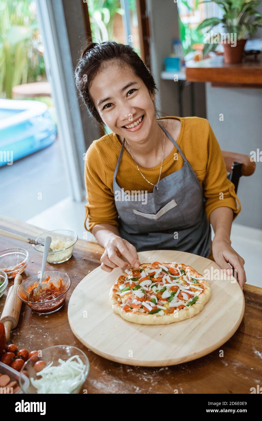 Young woman's hands make a pizza at home with vegetables, pepperoni and ...