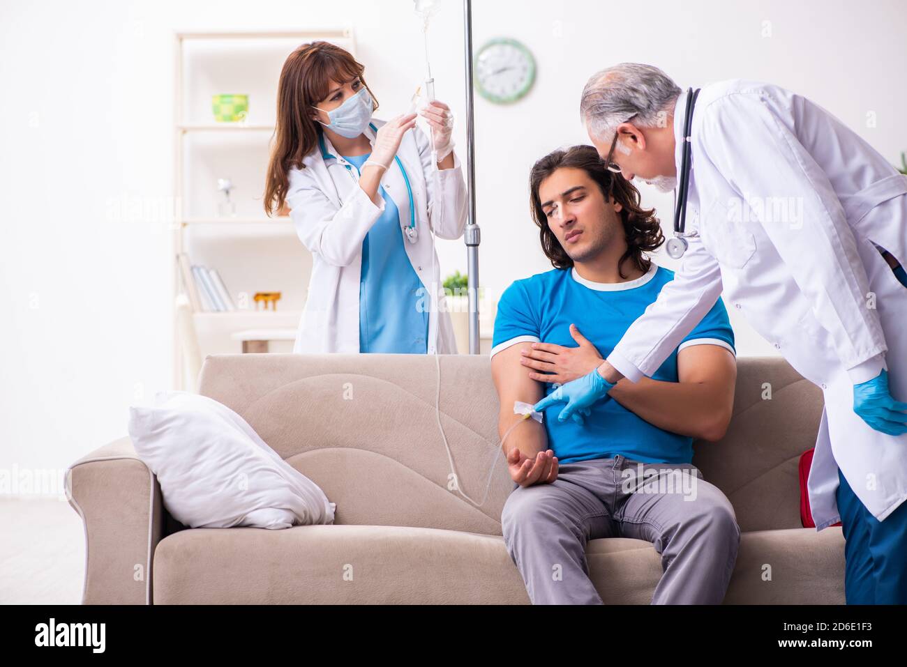 Two doctors visiting sick man at home Stock Photo - Alamy